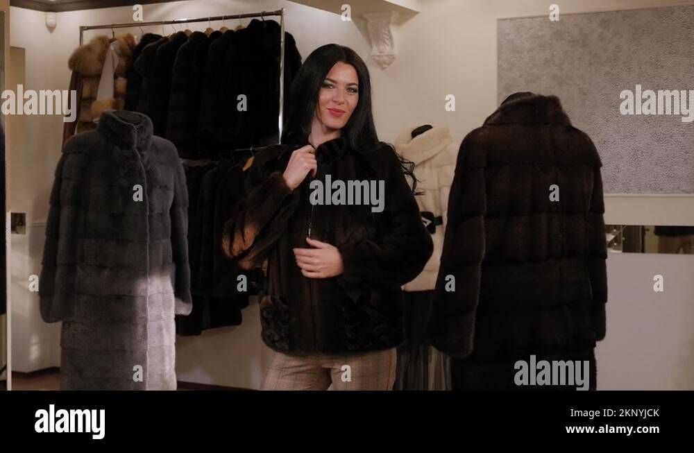 Happy woman chooses a new fur coat in the fur store in the shopping ...