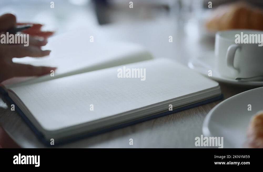 Woman hand taking notes writing pen notebook at remote workplace cafe ...