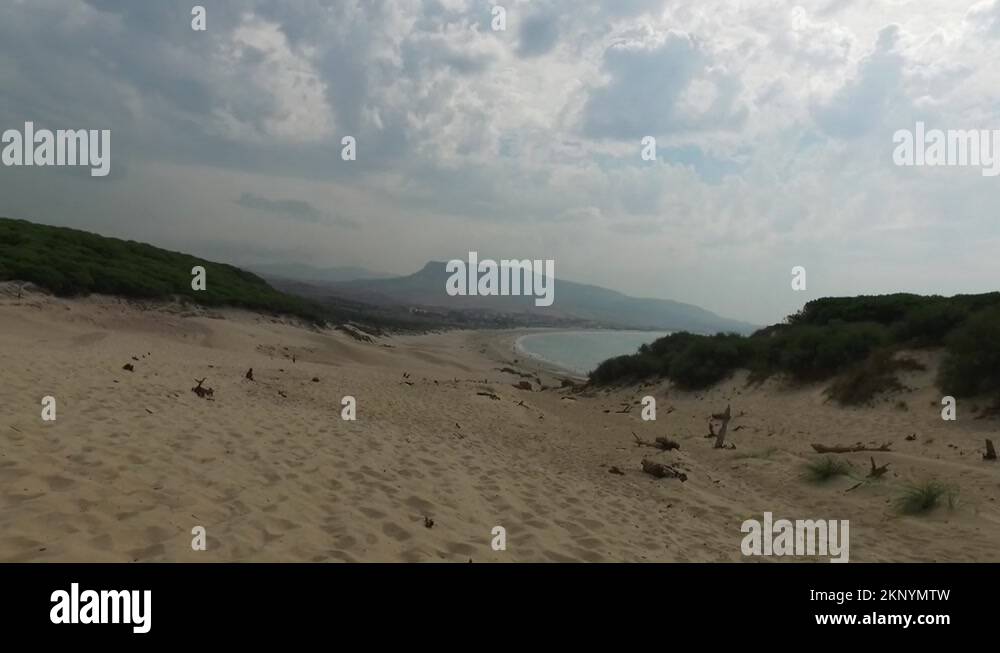 Camera descends the sand dune to the beach. The sea coast of Tarifa ...
