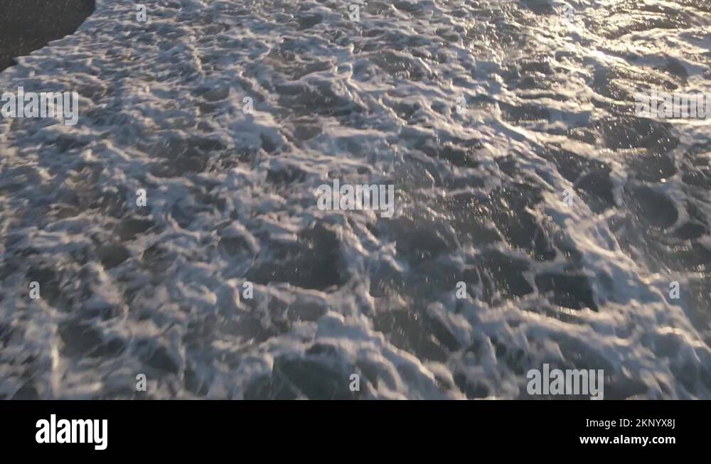 Foamy sea waves rolling over sandy beach, low altitude drone fly ...