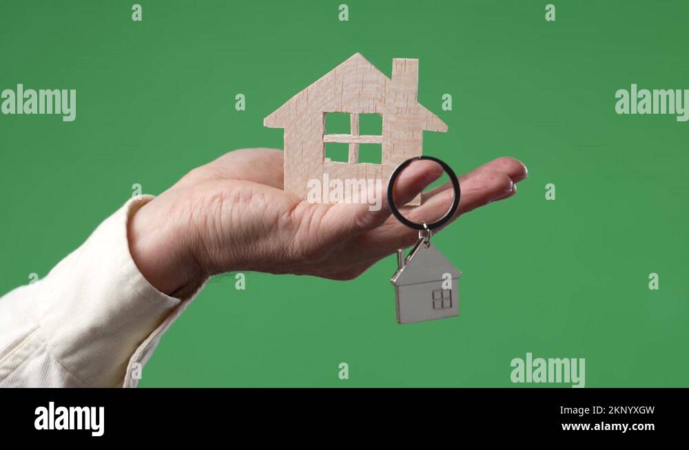 Hand holding house icon and dangling house keyring on green screen ...