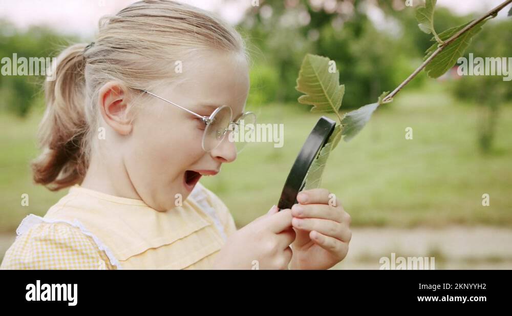 A teenage girl looks through the magnifying glass at the micro world of ...