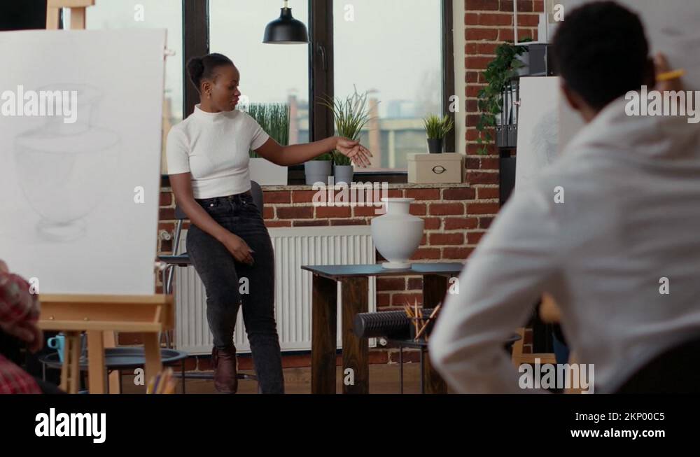Young artist pointing at vase model on table to teach drawing practice ...