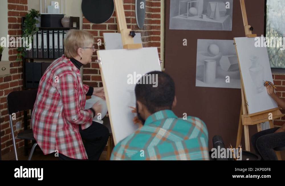 Elder teacher explaining drawing technique to students in art class ...