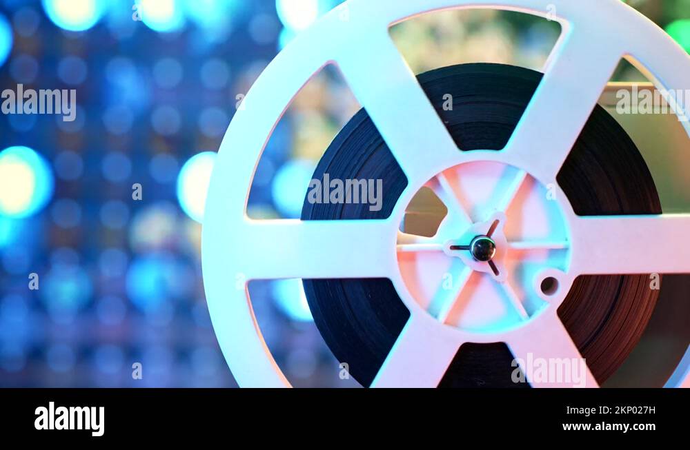 Retro reel with film rotating on sequins kinetic wall, neon light. Old ...