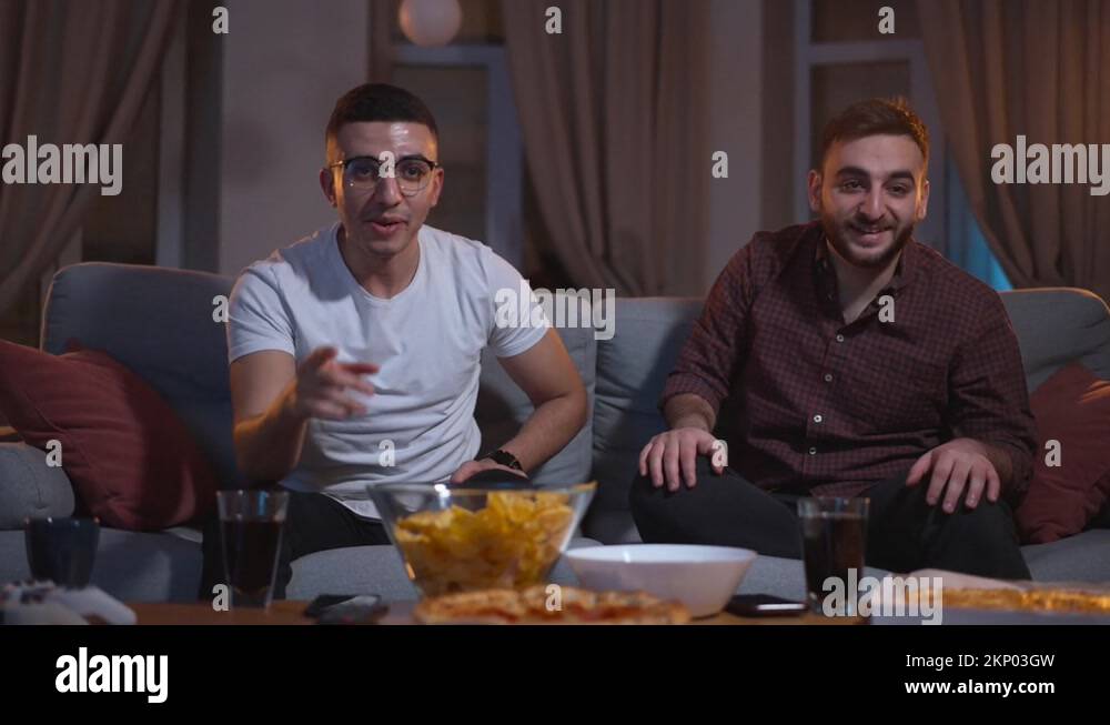 Two men watching TV match and showing positive emotions on couch in ...