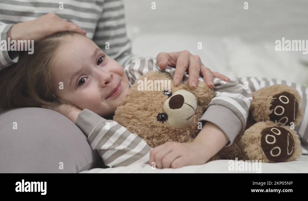 Small girl falls asleep lying on mother lap hugging teddy bear. Time to ...