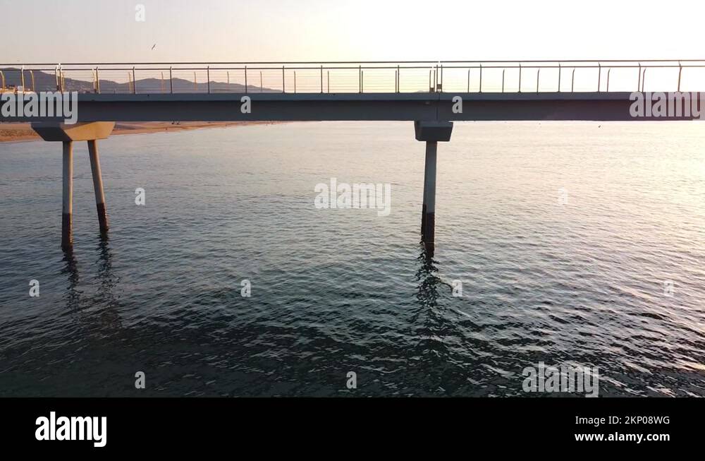 Side view of a jetty at the beach, flying alongside the metallic ...