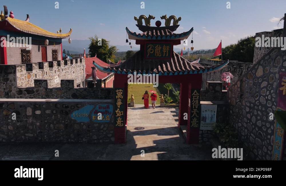 Two local Chinese walk under a red Chinese gate in the traditional ...