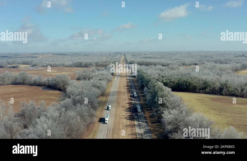 Descending aerial over remote stretch of interstate highway with trees ...