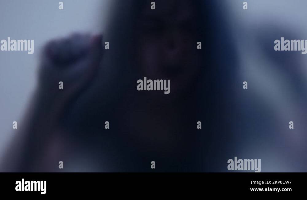 Defocused shot of Scary woman in despair behind glass emotional pain ...