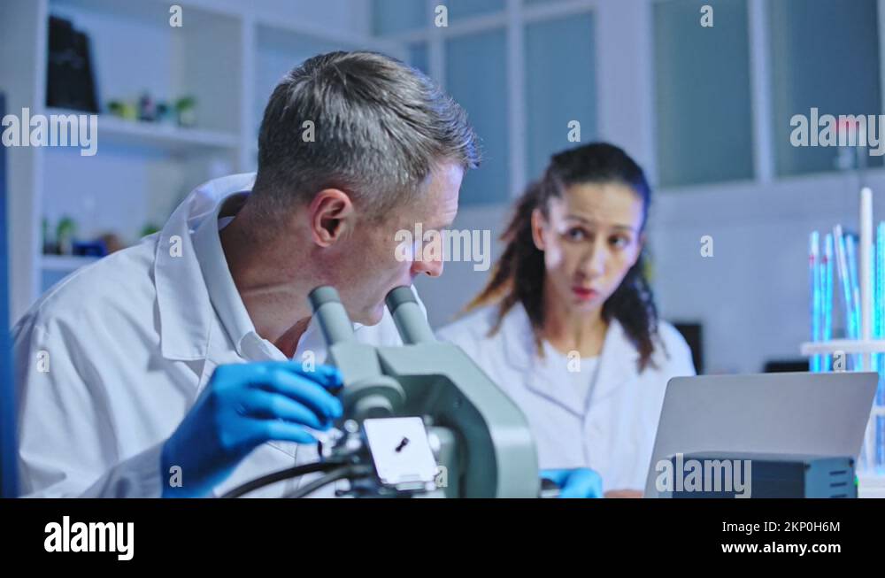 Oncology doctor examining tissue sample under microscope clinical ...