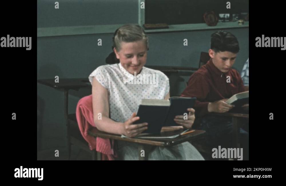 1950s: Kids reading in classroom, girl sits, opens book. Woman with ...