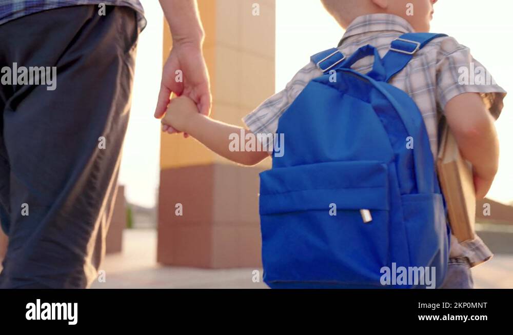 A schoolboy with a school backpack goes to school with his dad. Happy ...