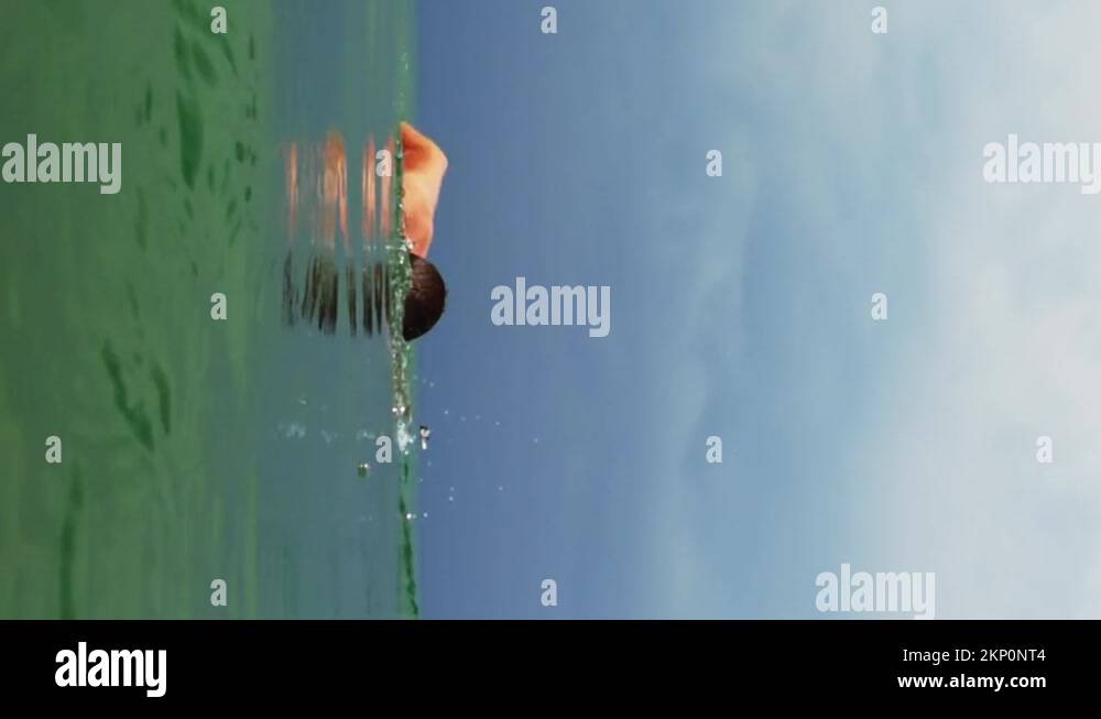 Male swimmer swimming in calm sea water. Low-angle sea-level view in ...