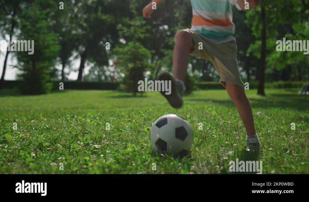 Happy boy play football on sunlight in park. Kid make soccer exercise on nature Stock Video ...