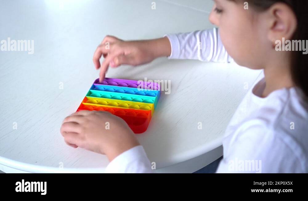 Baby girl playing with rainbow pop it fidget. The concept of mental ...