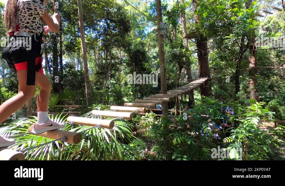 A young child balancing and walking across an obstacle course rope ...