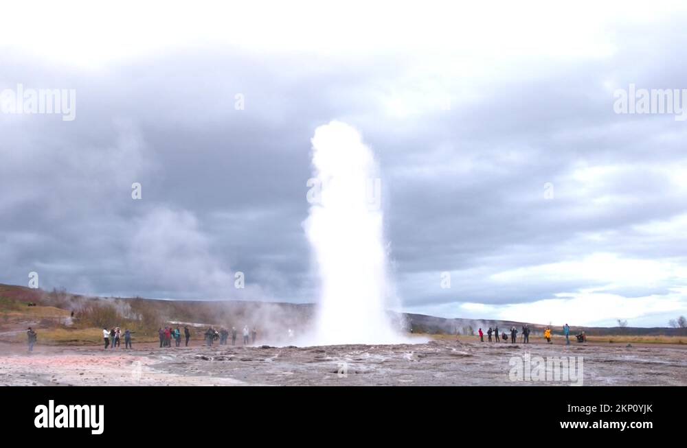 Tourists watching the Strokkur geyser in Iceland spouting hot water ...