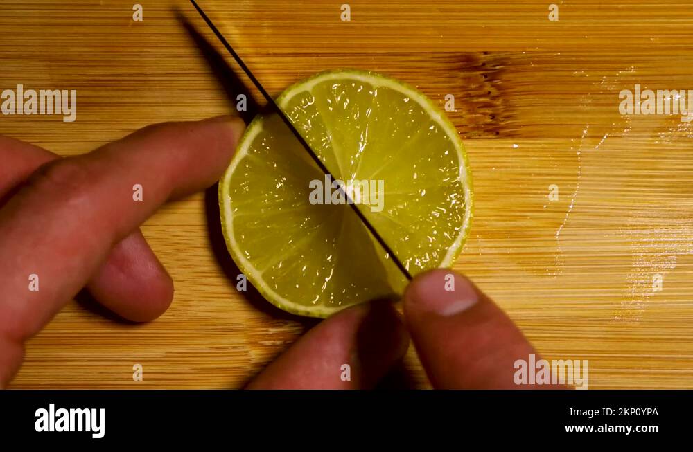 Cutting a lime in half. Green tropical fresh lime fruit cut in half ...