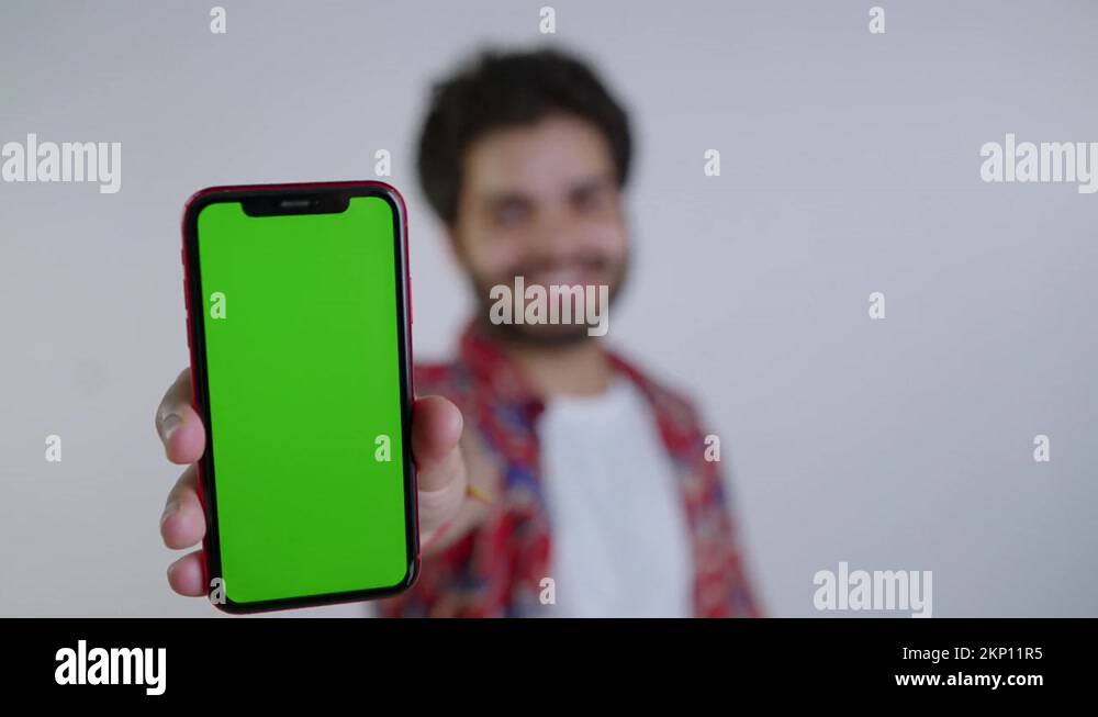 Young Indian man showing Chroma key on a Smartphone against white ...