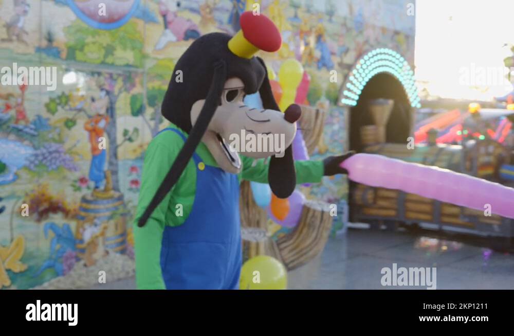 Men in Goofy and Mickey Mouse costumes entertain children with balloons ...