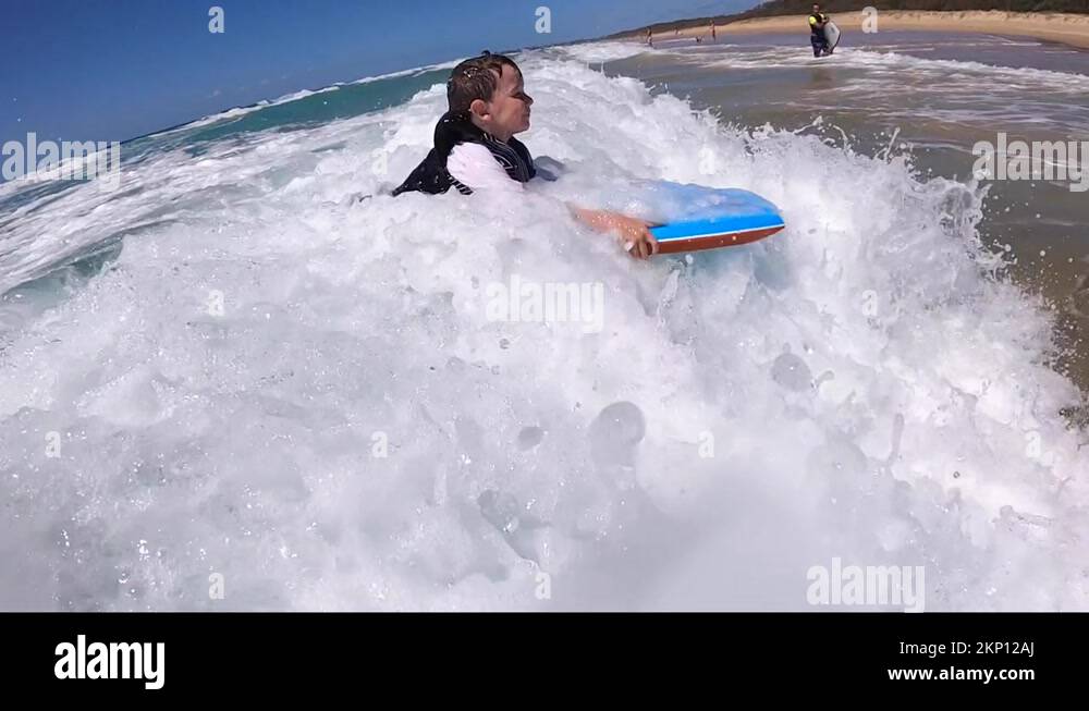 A young child bodyboarding at an Australian beach. Sunshine Coast Stock ...