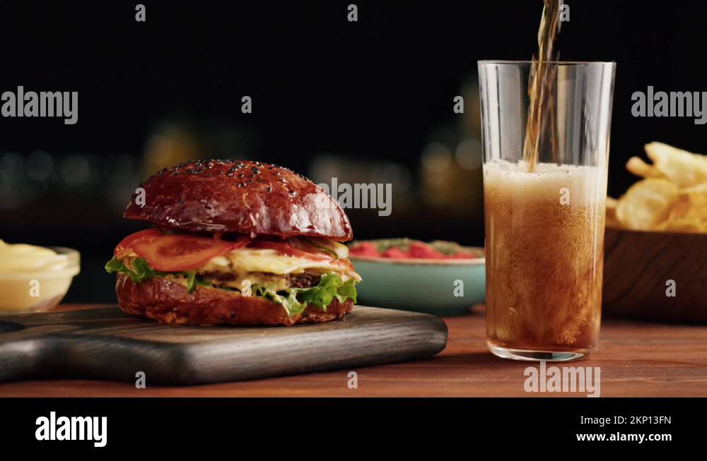 Tasty burger close-up, pouring lemonade into glass, cooked juicy ...