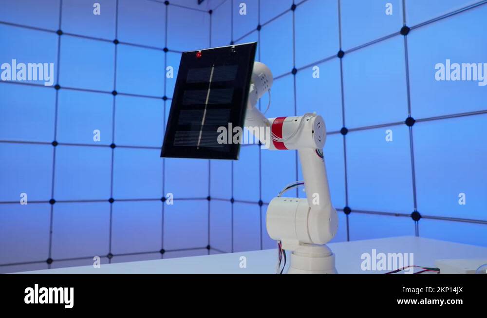 Solar panel in the robot arm. Robot holding a solar panel on a blue lab ...