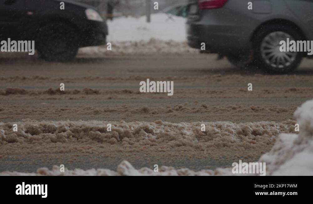 City roads during heavy snowfalls. Cars drive through winter mud and ...