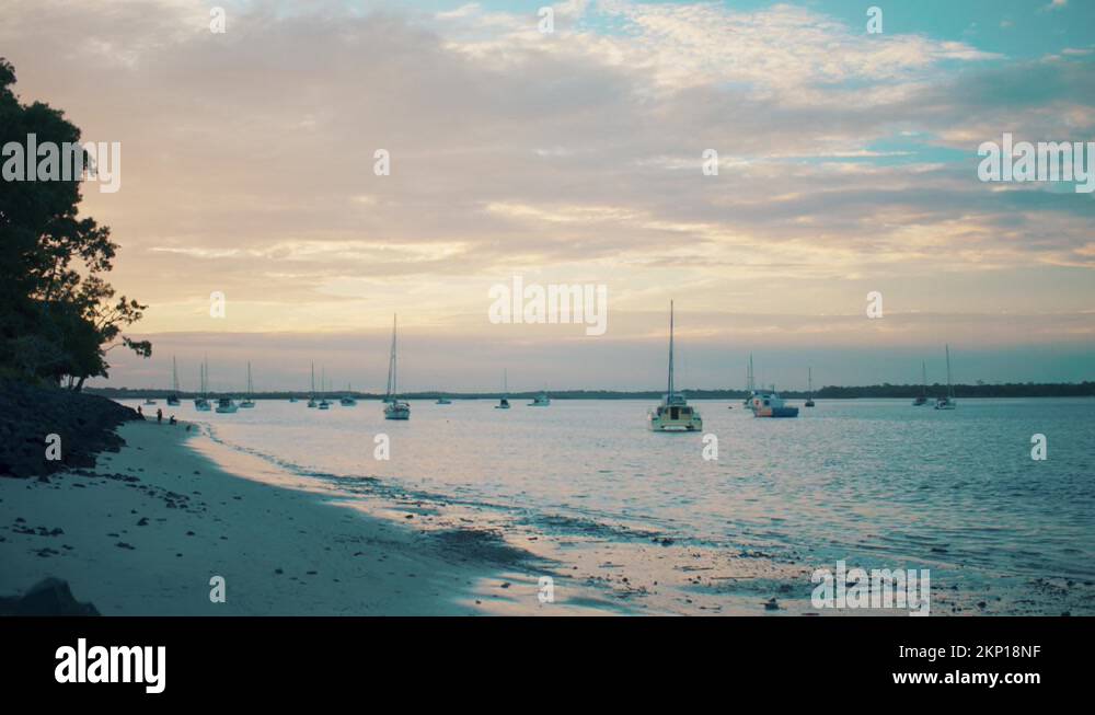 Dozens of small boats float upon the surface of the ocean just shy off ...
