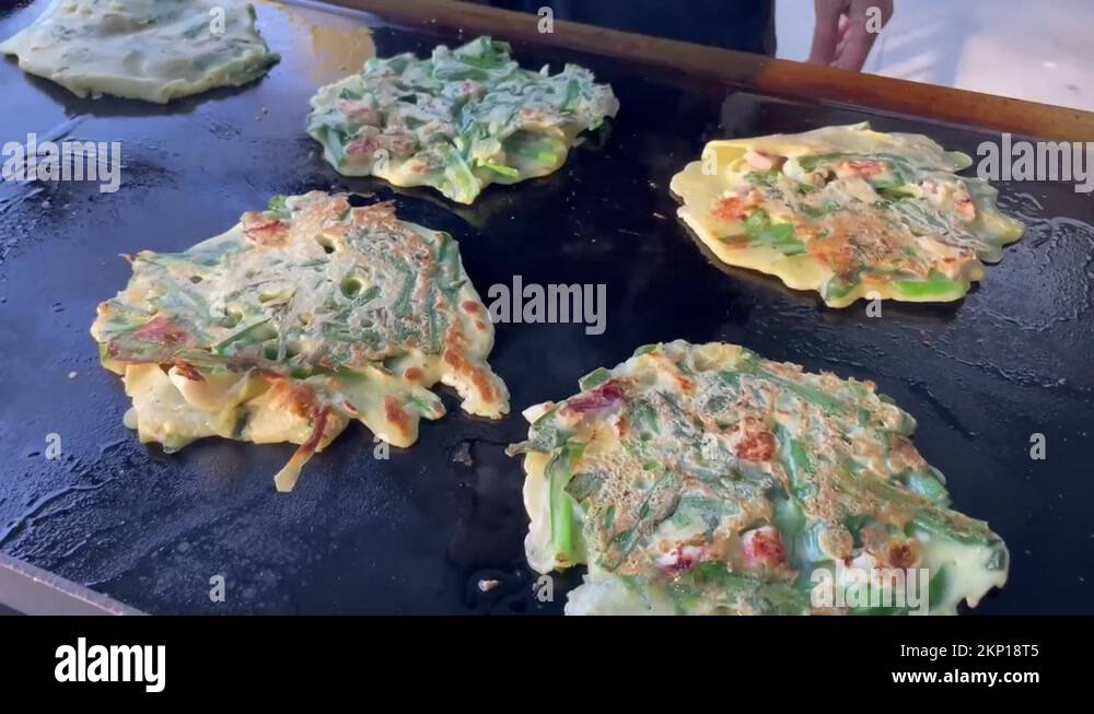 Korean seafood scallion pancakes (Street Food) browning over a open top ...