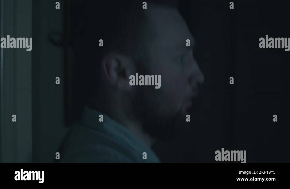 A young man with a light beard speedily runs around a corner and ...