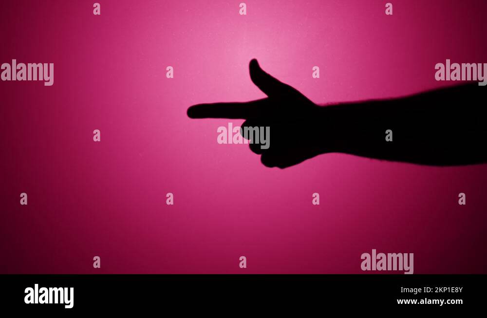 Shadow of hand showing gun with fingers on pink neon background. Man ...