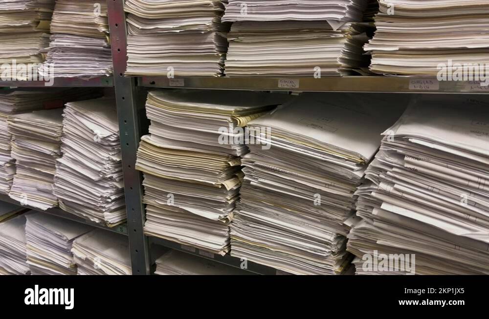 in a file archive there are shelves filled with stacks of paper Stock ...