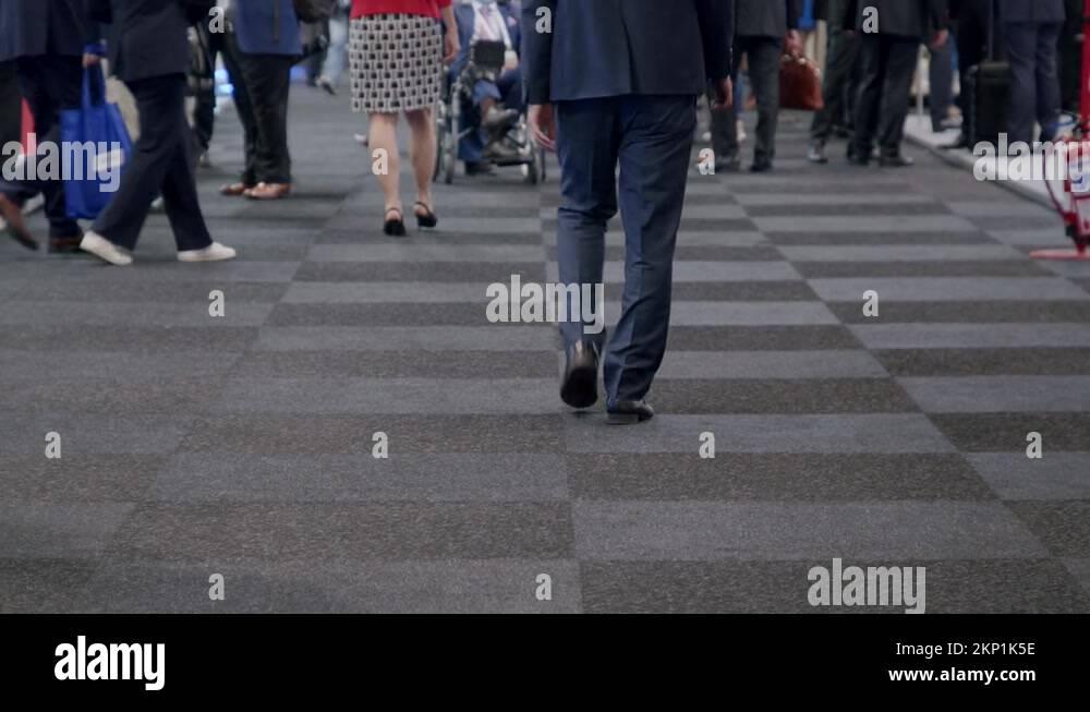 Real time, full-body shot, tilting up camera, attendees at busy trade ...
