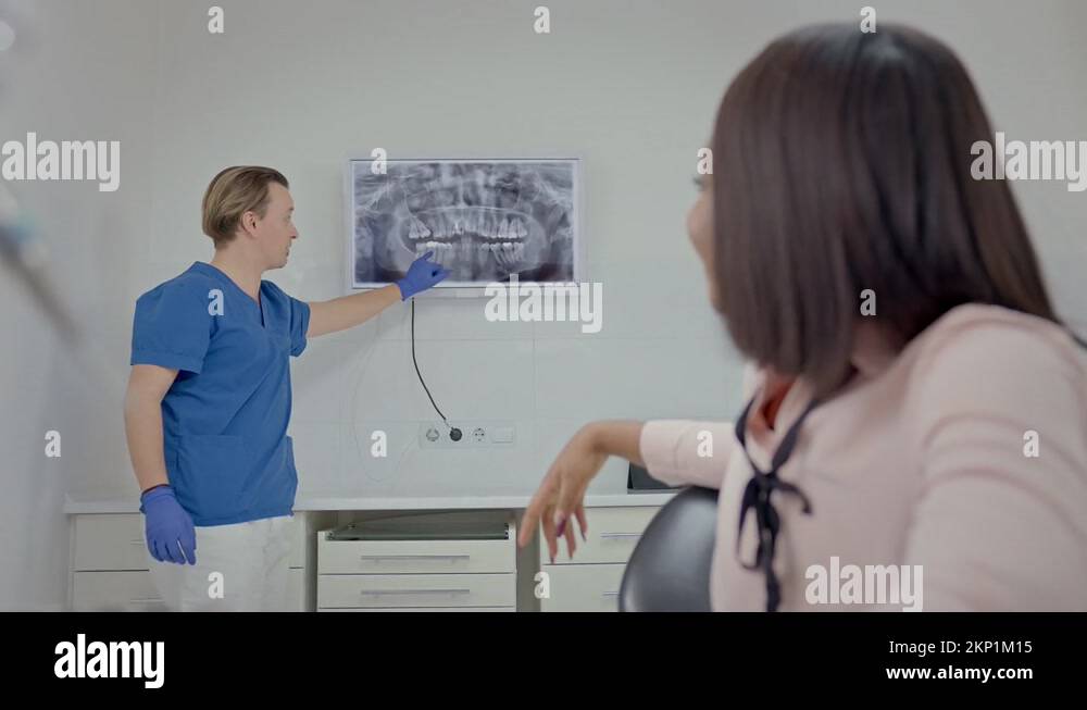 Male Dentist In Dental Office Shows Patient Image Of Her Teeth On Big ...