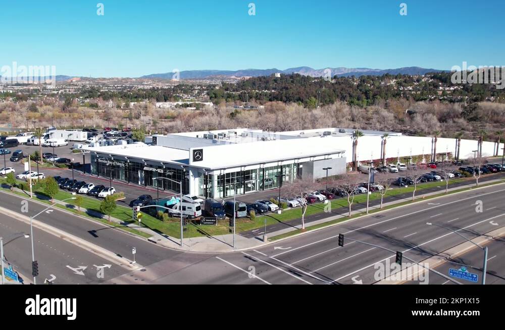 Ascending aerial view of a car dealership on an intersection with a ...