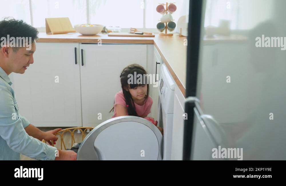 Asian happy family stay home, father teach daughter wash dirty clothes ...