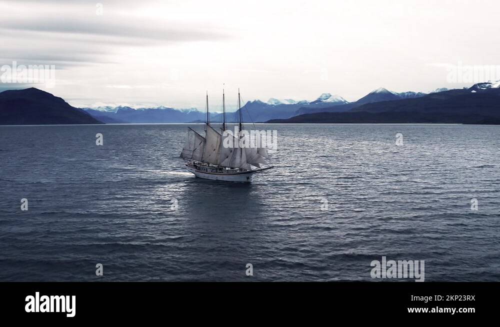 An aerial view of the old sailing ship crossing the fjord. Snow-capped ...