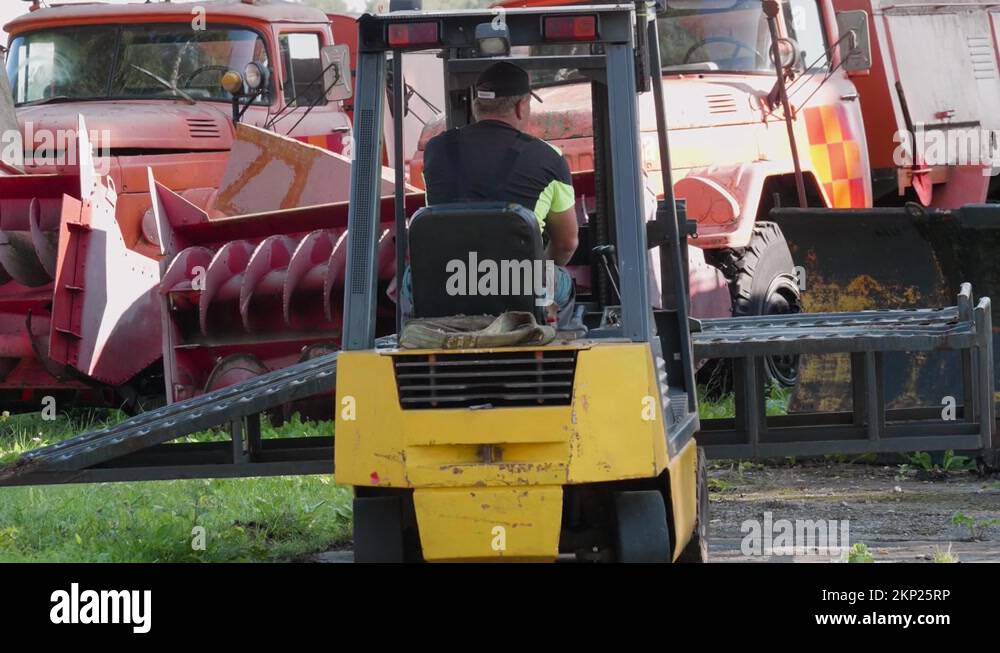 Driver with forklift handling vehicle service ramps in front of old ...