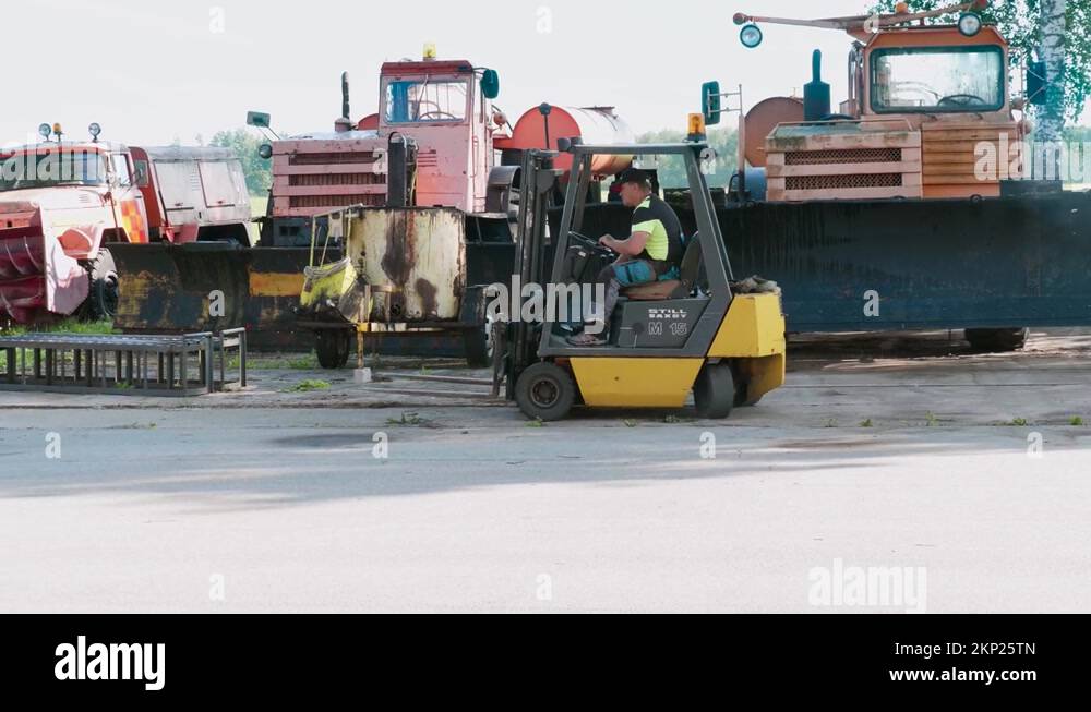 Forklift handling vehicle service ramps in front of old heavy trucks in ...