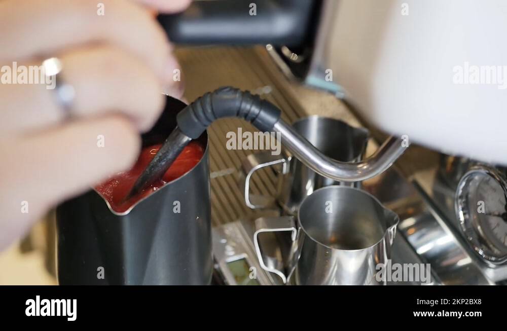 Barista prepares raspberry tea by heating steam from a coffee machine ...