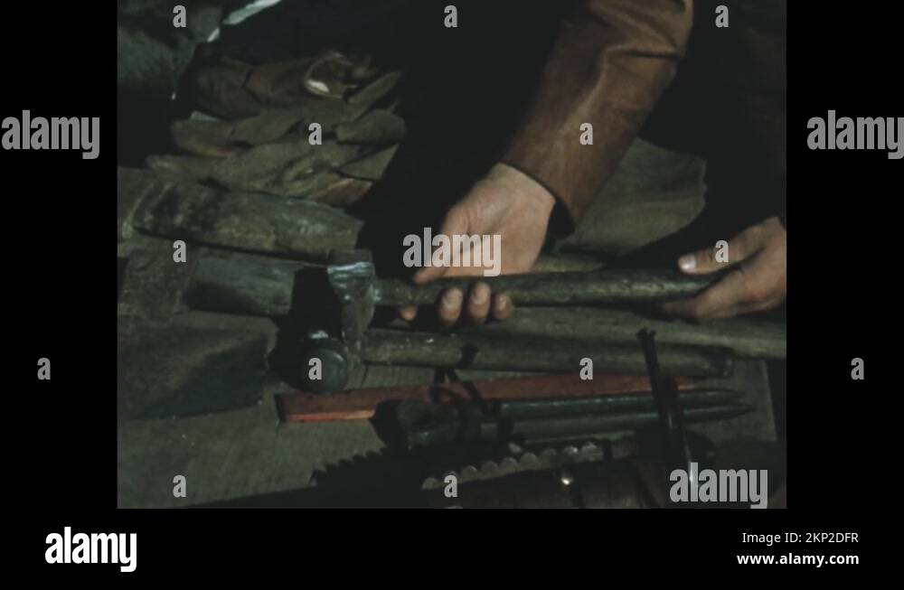 Holland 1960s: A selection of weapons and tools. Hands pick up a musket ...