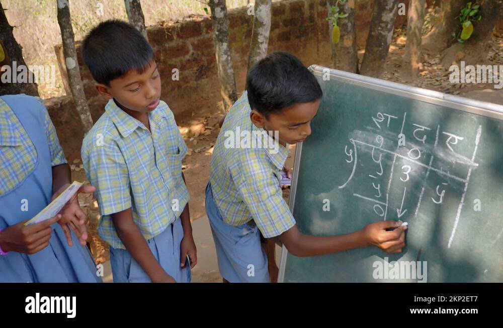 Indian Rural school boys and girls wearing uniforms doing group studies ...