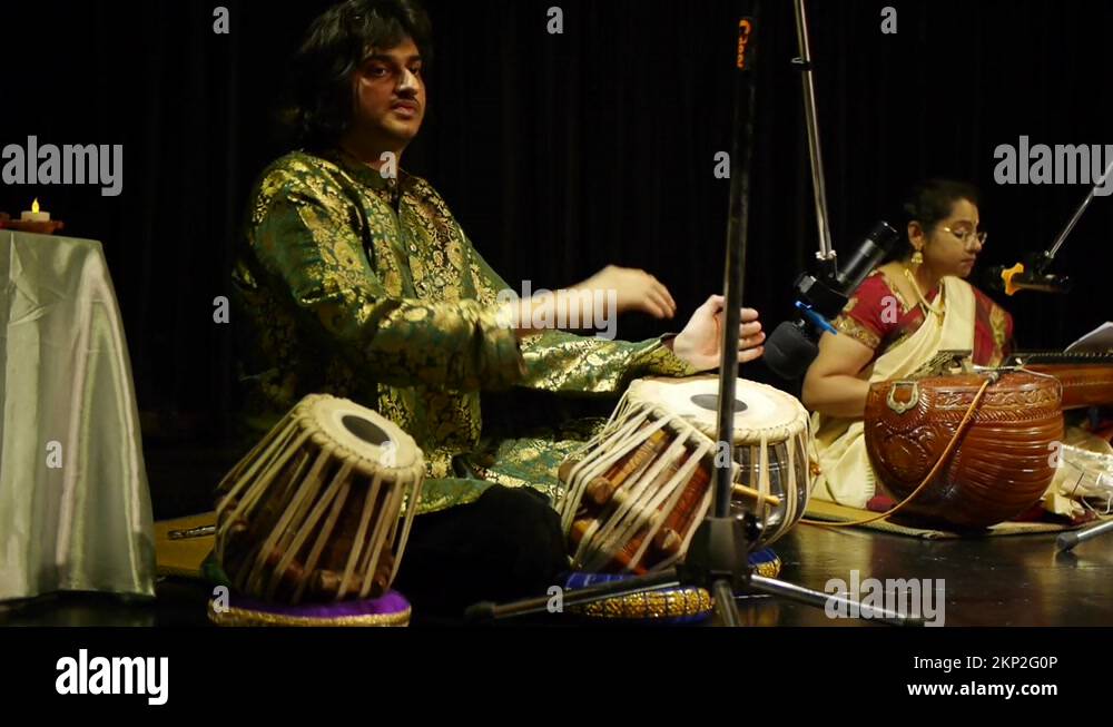 Indian man dressed in traditional Indian silk clothing tapping tablas ...