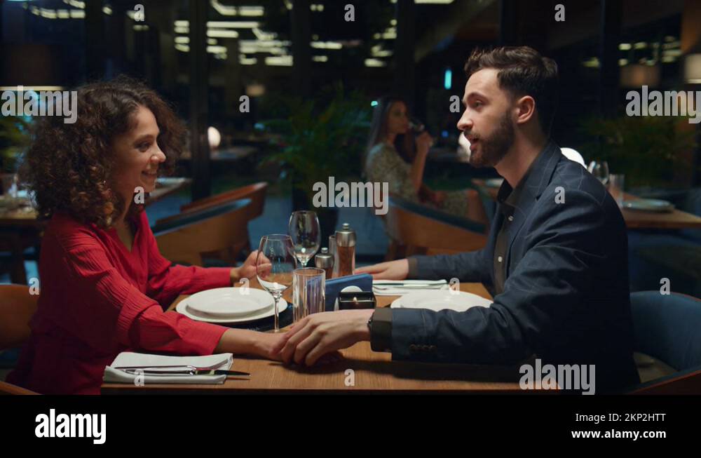 Flirting couple hold hands in restaurant. Man kissing girlfriend on ...