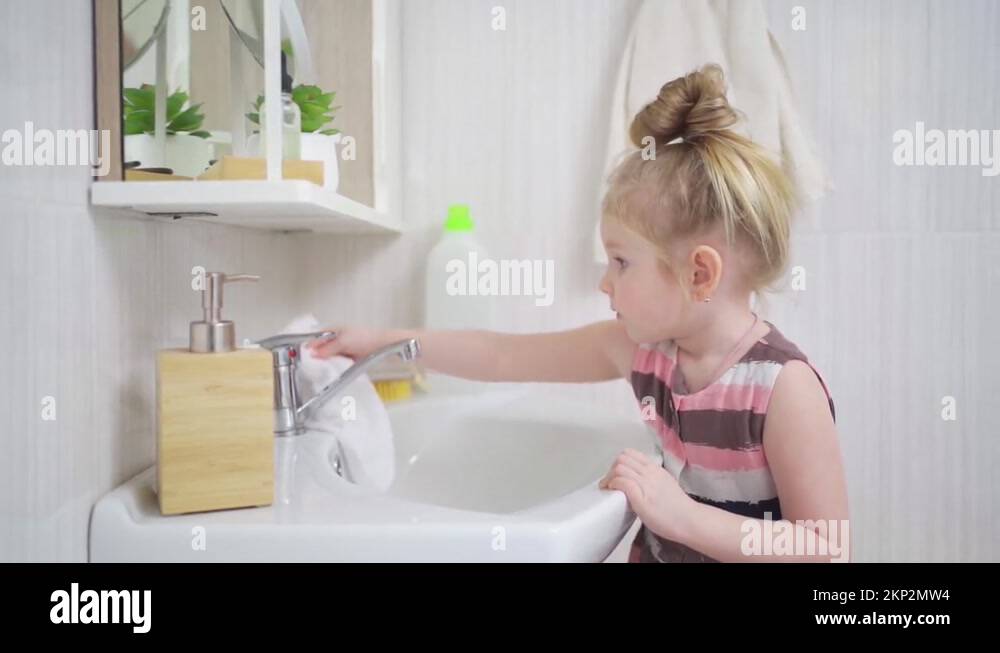 a cute little girl washes sink and the bathroom mirror with a special ...