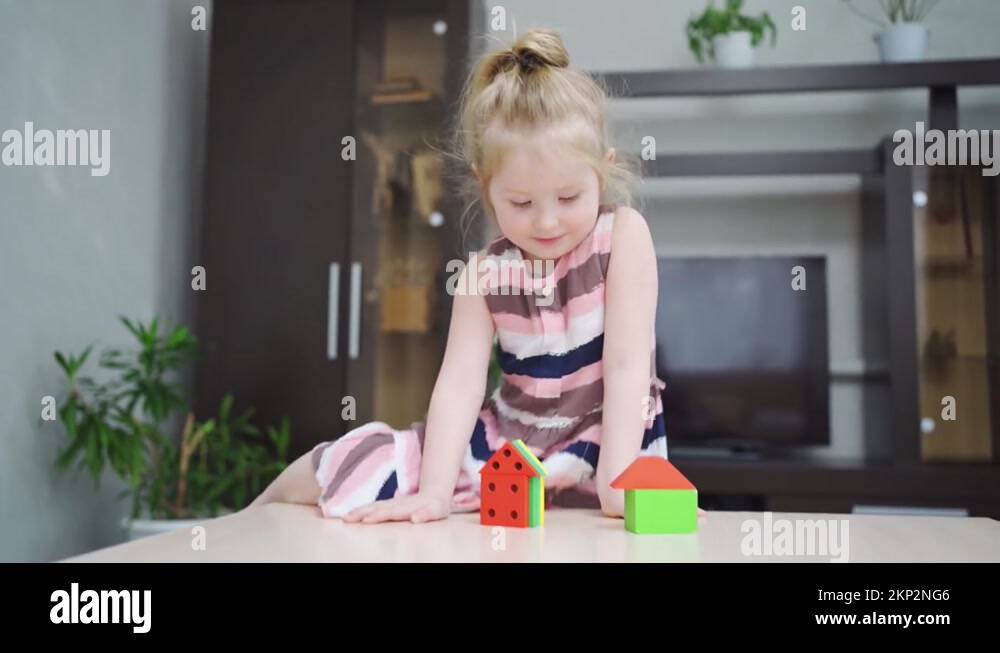 a cute little girl builds houses from a colorful wooden construction ...