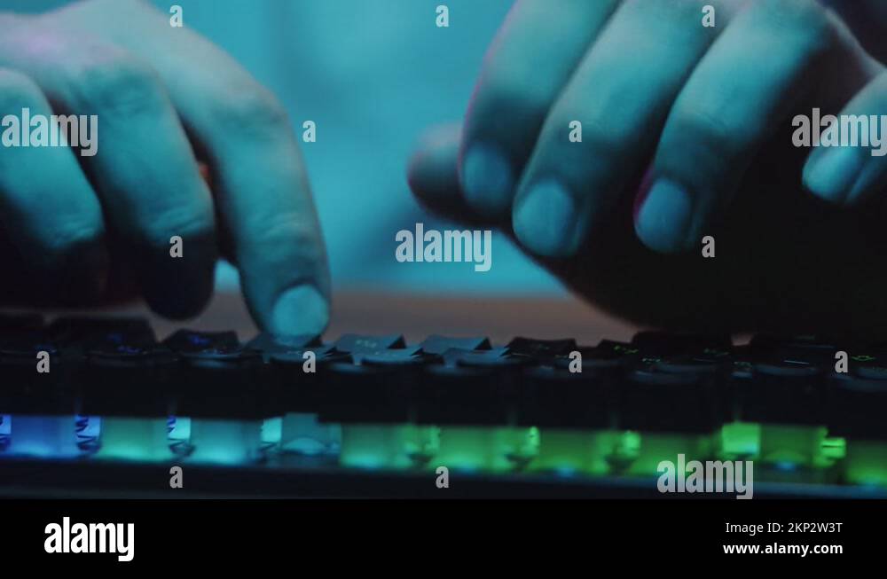 Gamer typing on backlight keyboard close-up, man playing video game ...